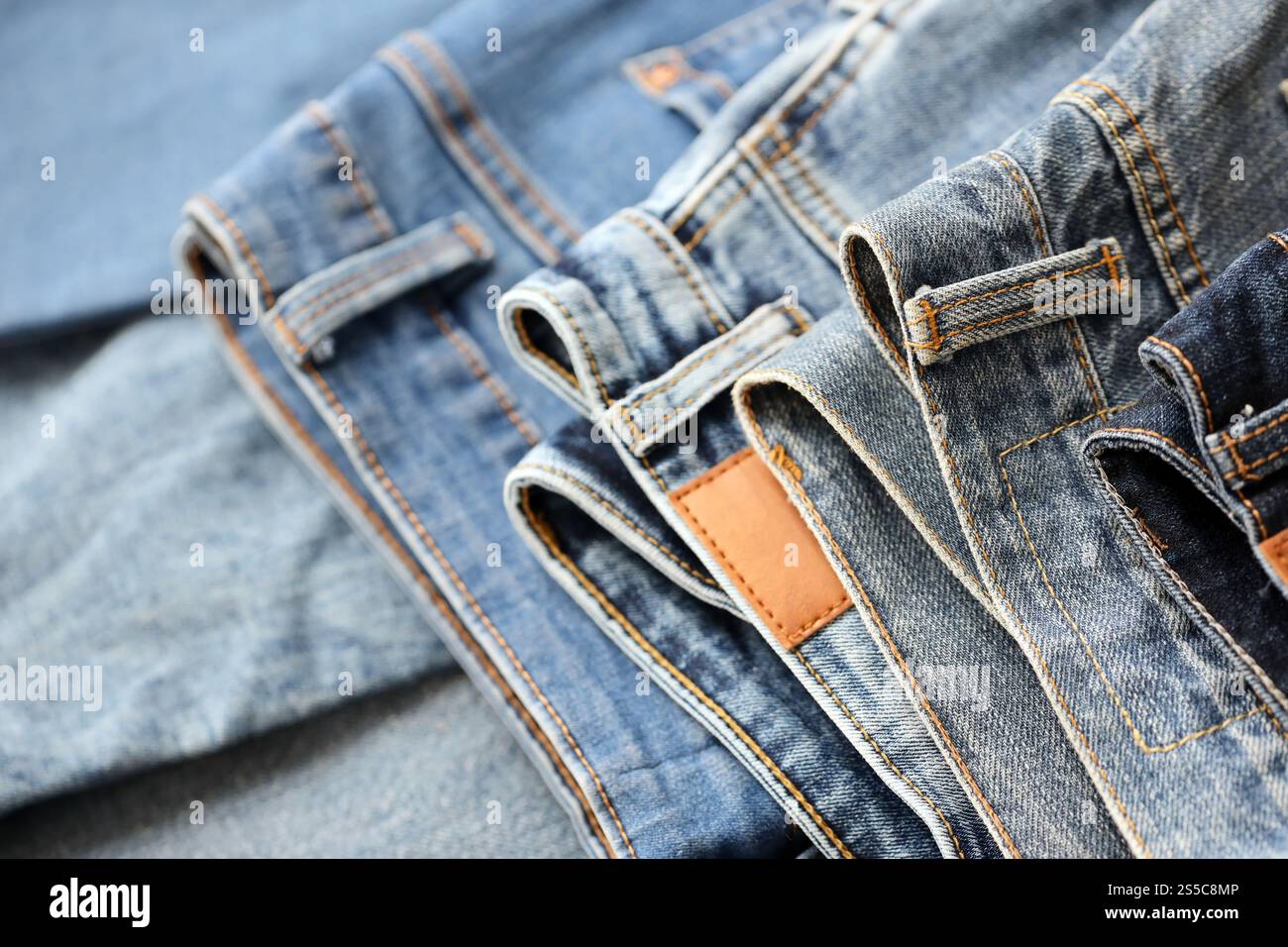 Many jeans in stack in wardrobe room. Row of pants denim jeans in ...