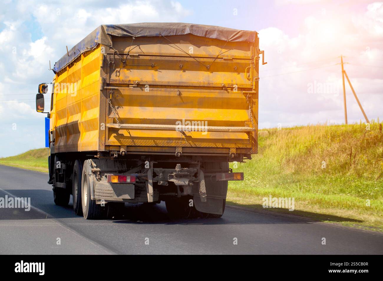 A yellow dump truck transports grain from the fields with a closed ...