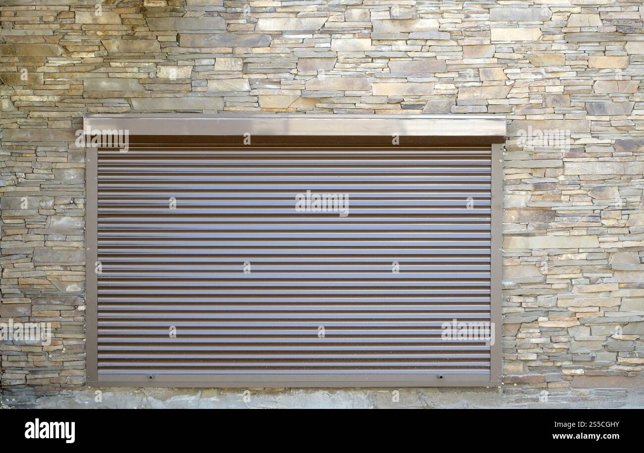 A window with brown metal rolling shutters. Wall decoration with ...