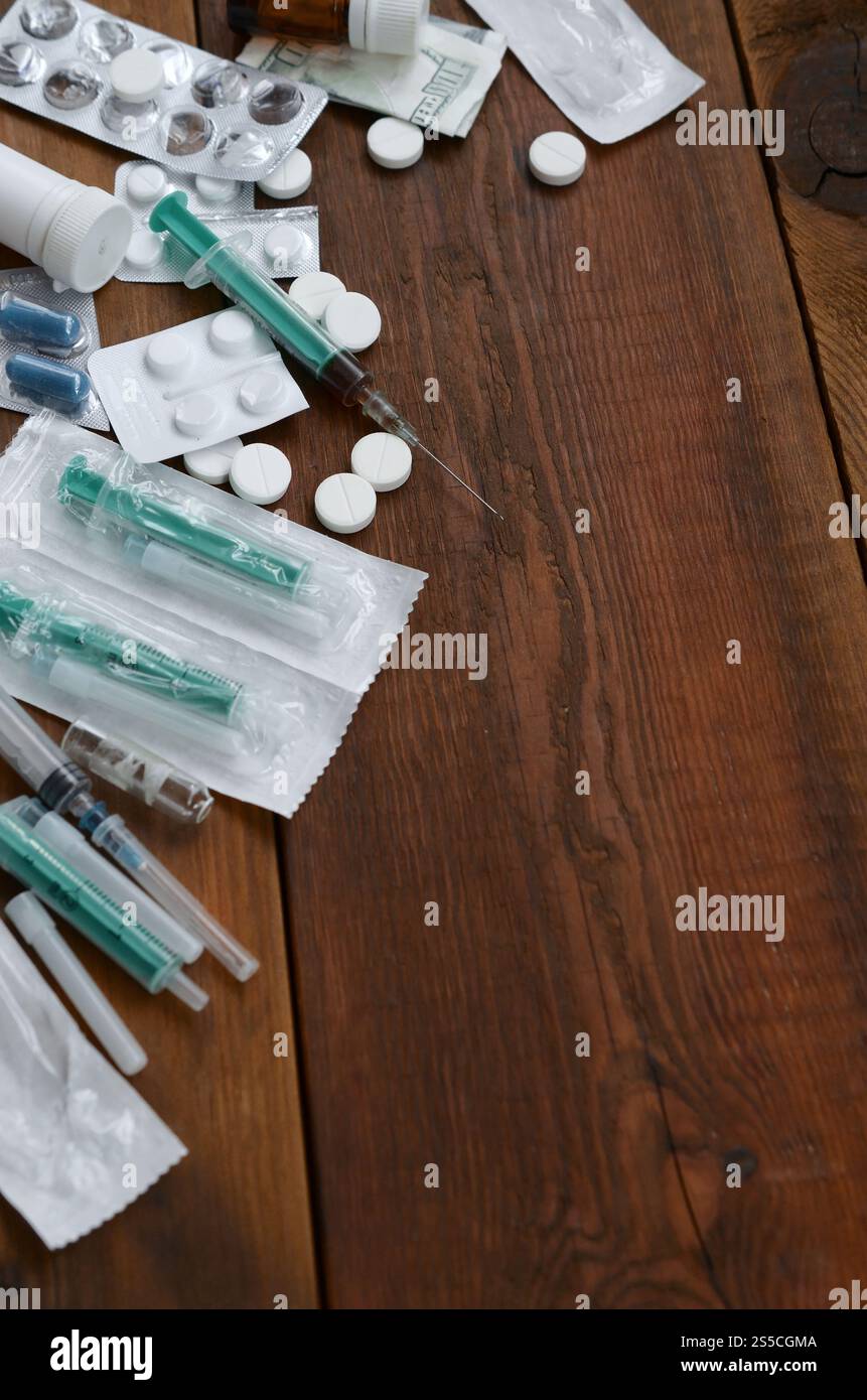 Narcotic stuff with many pills and syringes lies on wooden table and ...