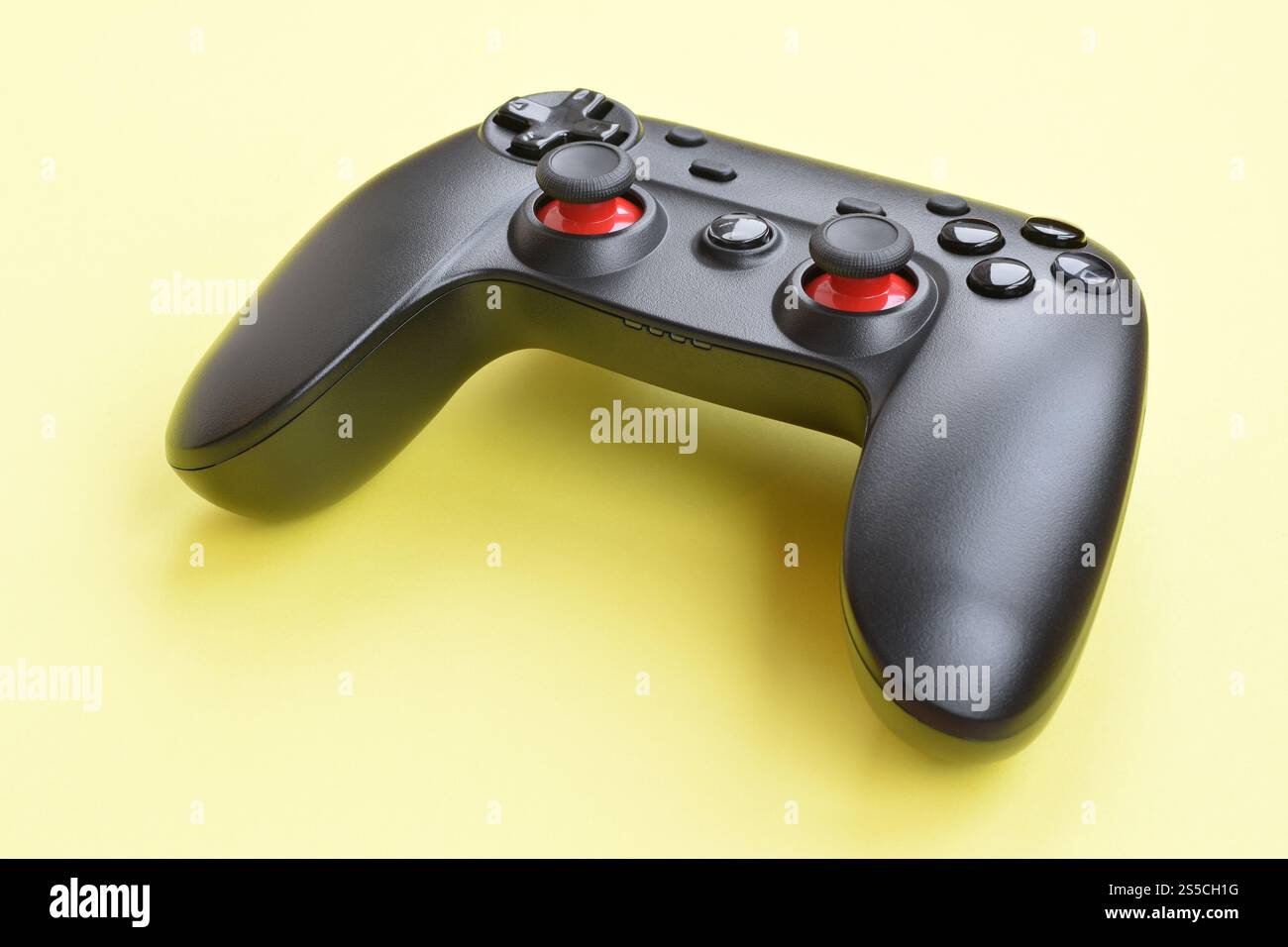 Modern black video game controller on yellow background close up ...