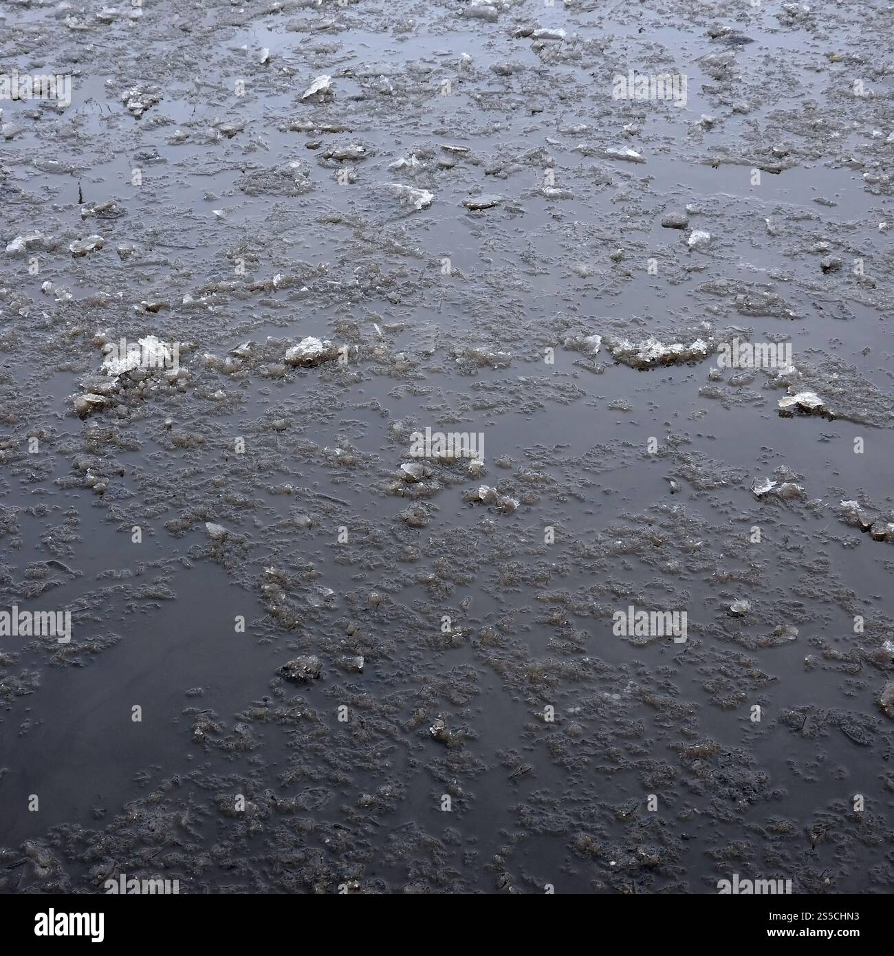 Damaged asphalt road with potholes, filled with water with ice, caused ...