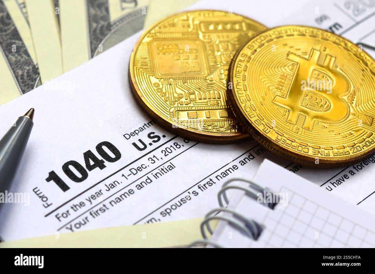 The pen, bitcoins and dollar bills is lies on the tax form 1040 U.S ...