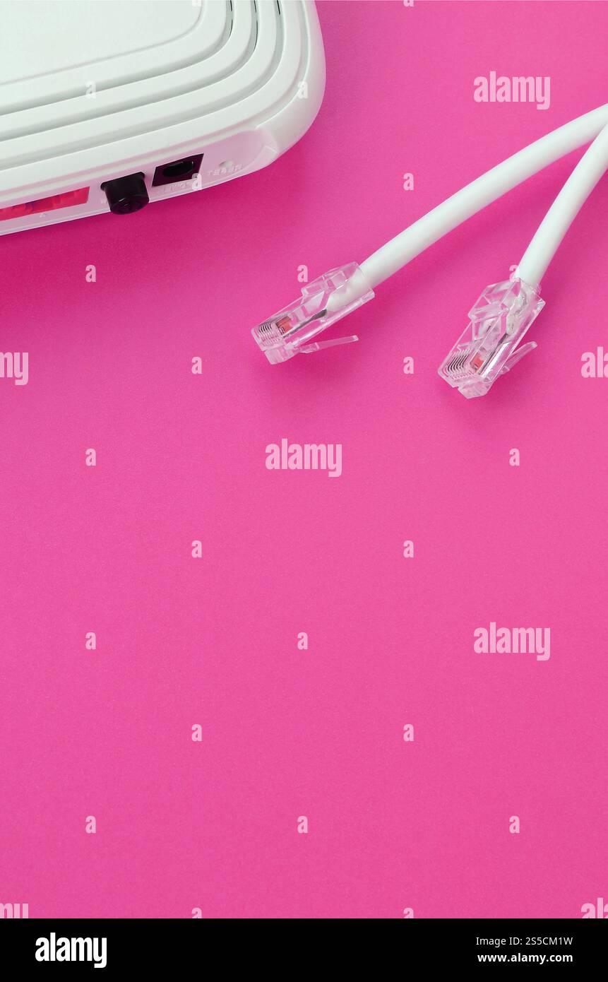 Internet router and Internet cable plugs lie on a bright pink ...