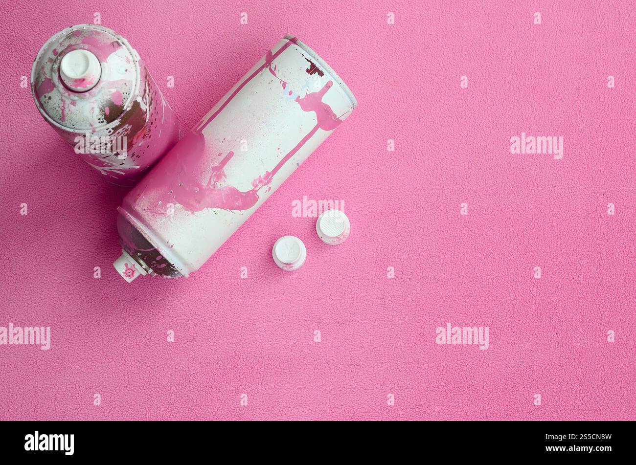 Some used pink aerosol spray cans and nozzles with paint drips lies on ...