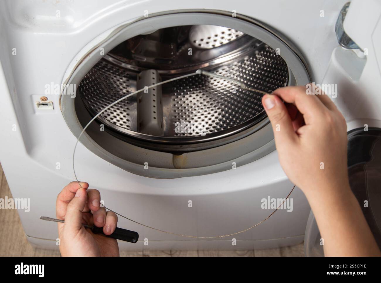 The technician changes the rubber seal of the hatch in the washing ...