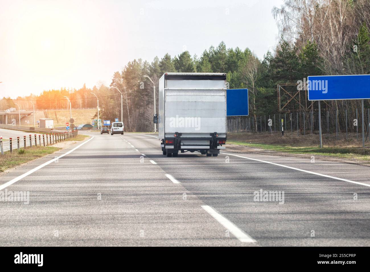 A modern van with a tail lift is driving along an asphalt road against ...