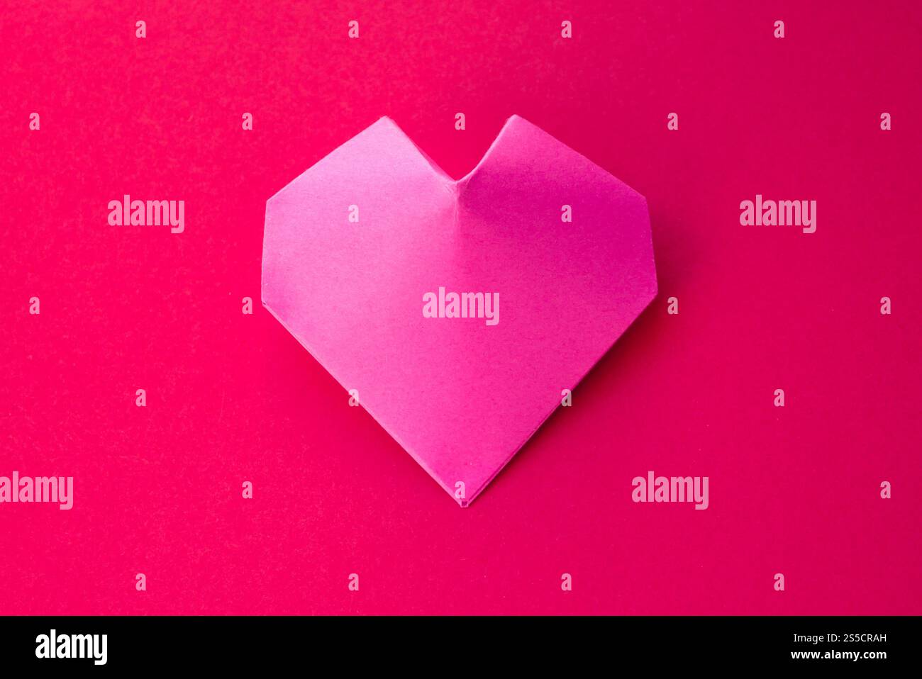 Pink paper heart origami isolated on a blank red background. Valentines ...