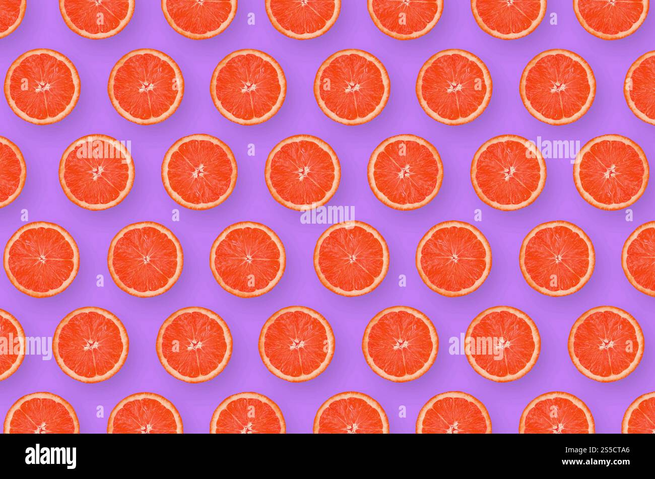 Top view of grapefruit slices on bright purple background. A saturated ...