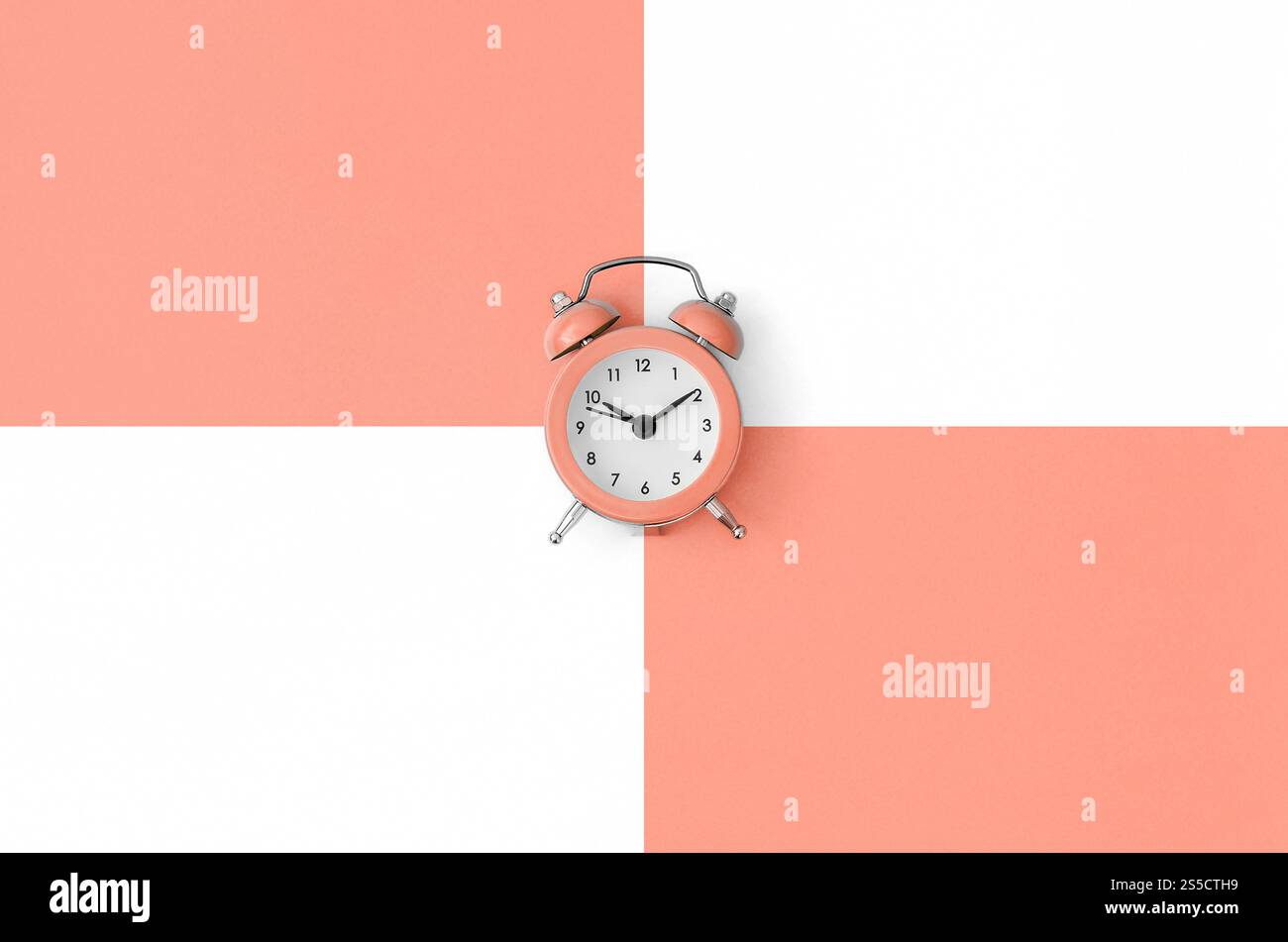 A small coral alarm clock is located between areas of red and white ...