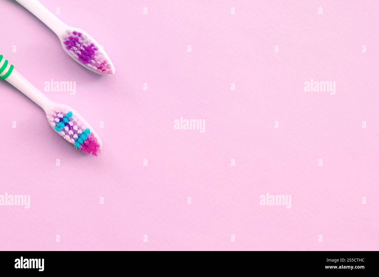 Two toothbrushes lie on a pastel pink background. Top view, flat lay ...