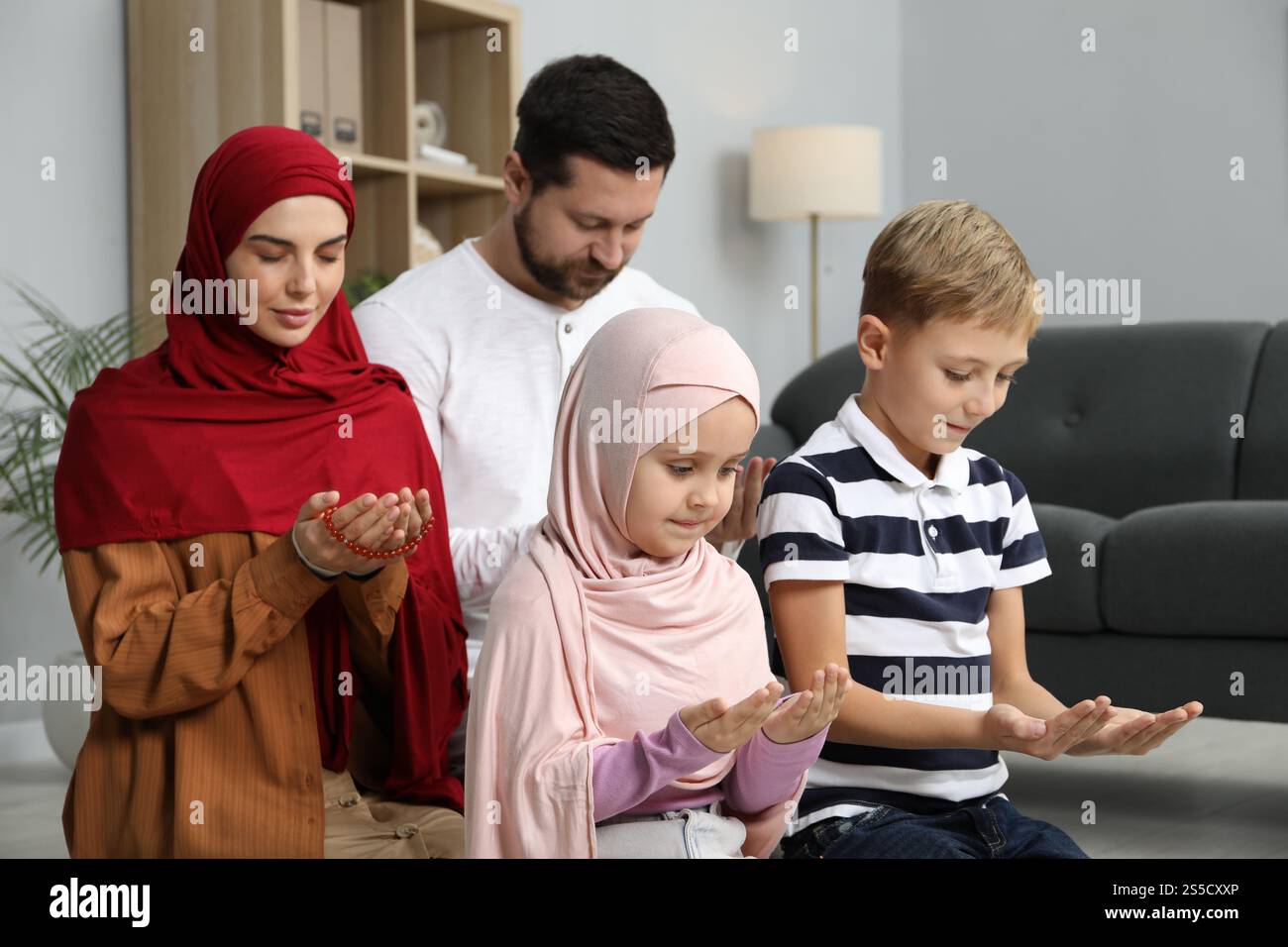 Happy Muslim family praying together at home Stock Photo - Alamy