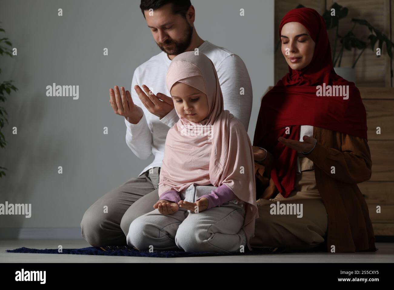 Muslim family praying on mat at home Stock Photo - Alamy