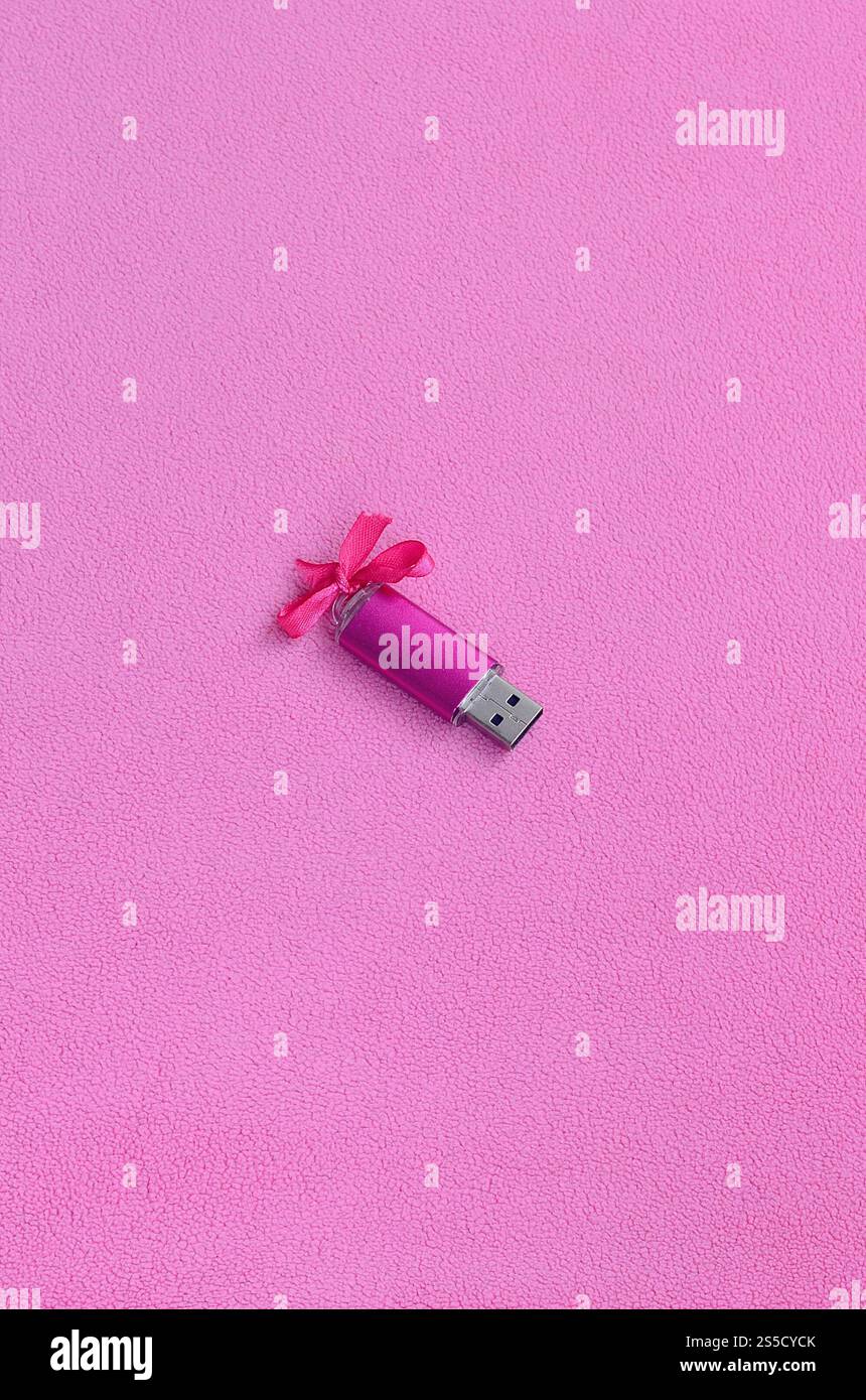 Brilliant pink usb flash memory card with a pink bow lies on a blanket ...