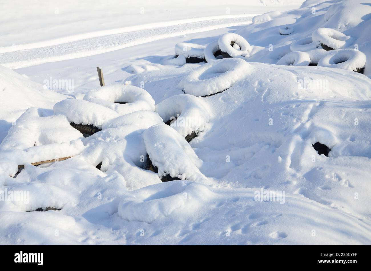 Used and discarded car tires lie on the side of the road, covered with a thick layer of snow ...