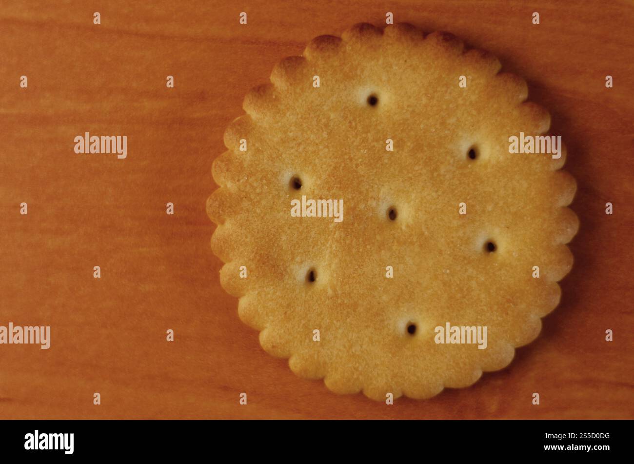 Background image of one classic salty cracker on a brown wooden table ...