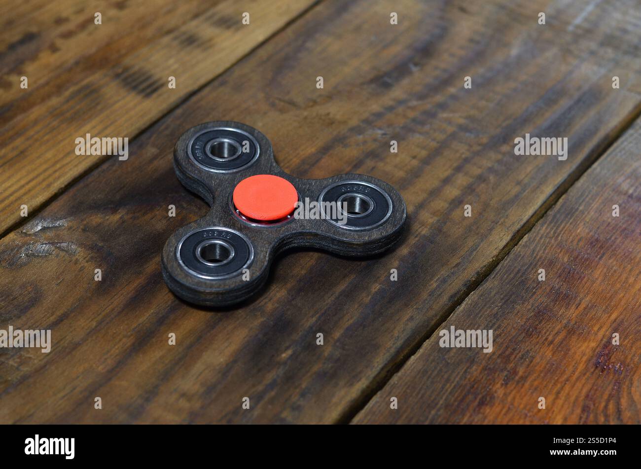 A rare handmade wooden fidget spinner lies on a brown wooden background ...