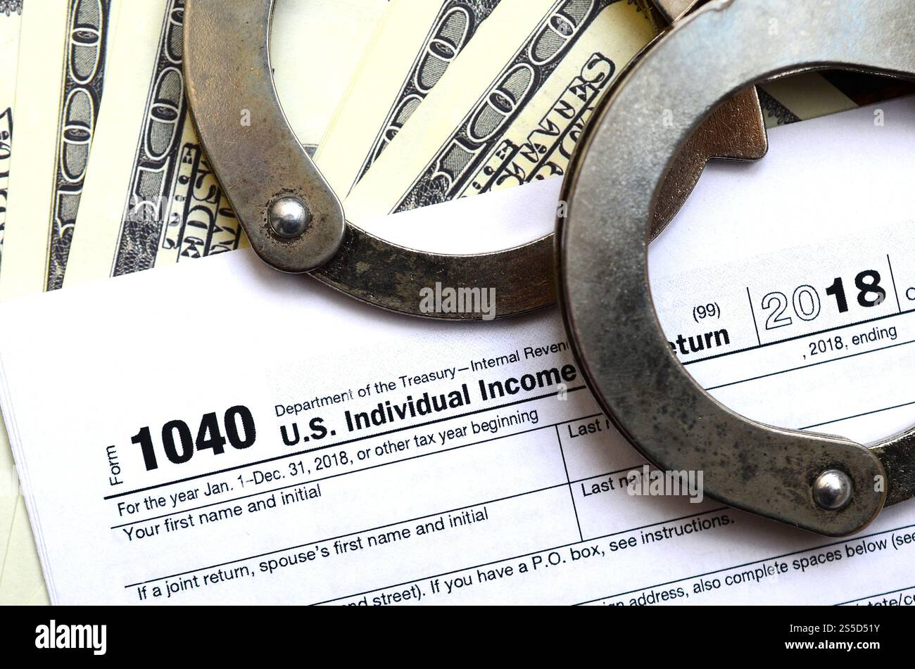 Police handcuffs lie on the tax form 1040. The concept of problems with ...