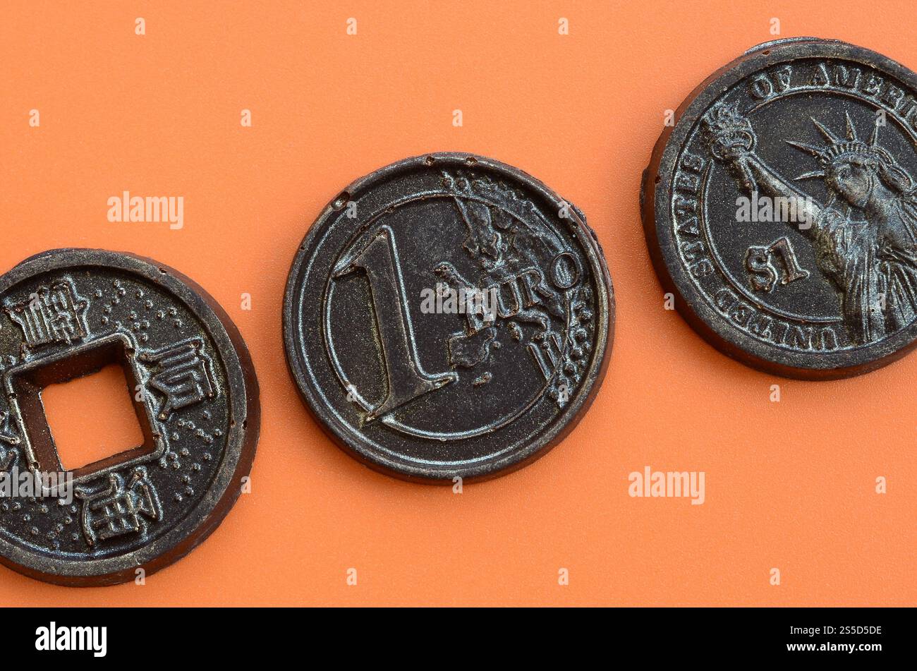 Three chocolate products in the form of Euro, USA and Japan coins lie ...