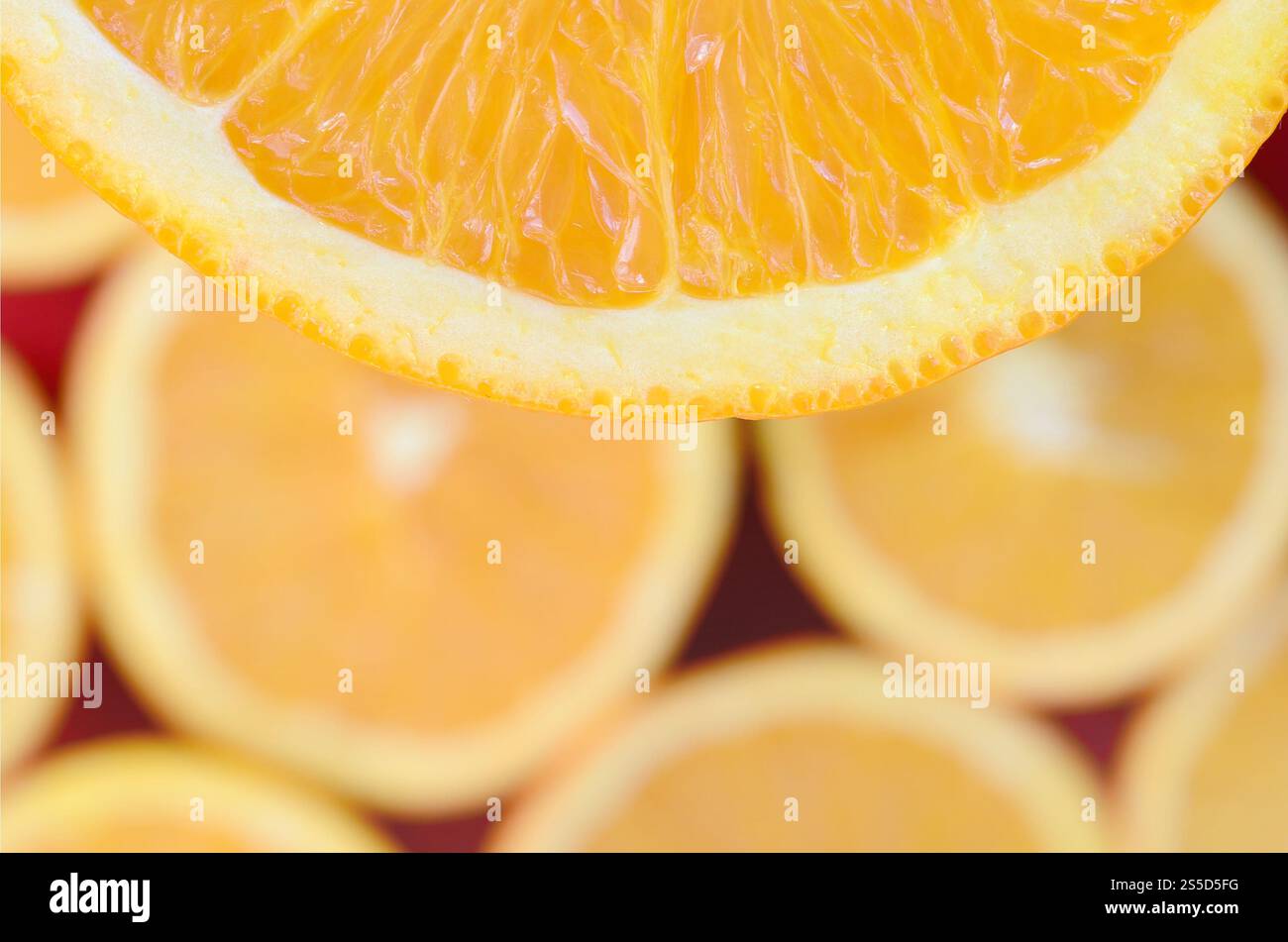Top view of a fragment of the orange fruit slice on the background of many blurred orange slices ...