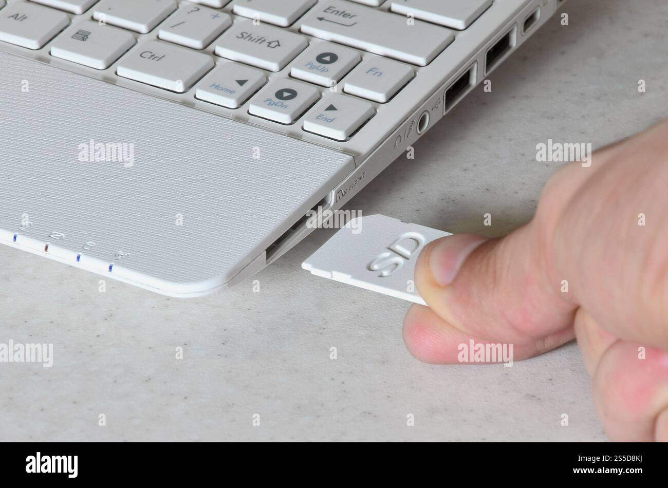 A male hand inserts a white compact SD card into the corresponding ... A male hand inserts a white compact SD card into the corresponding ...