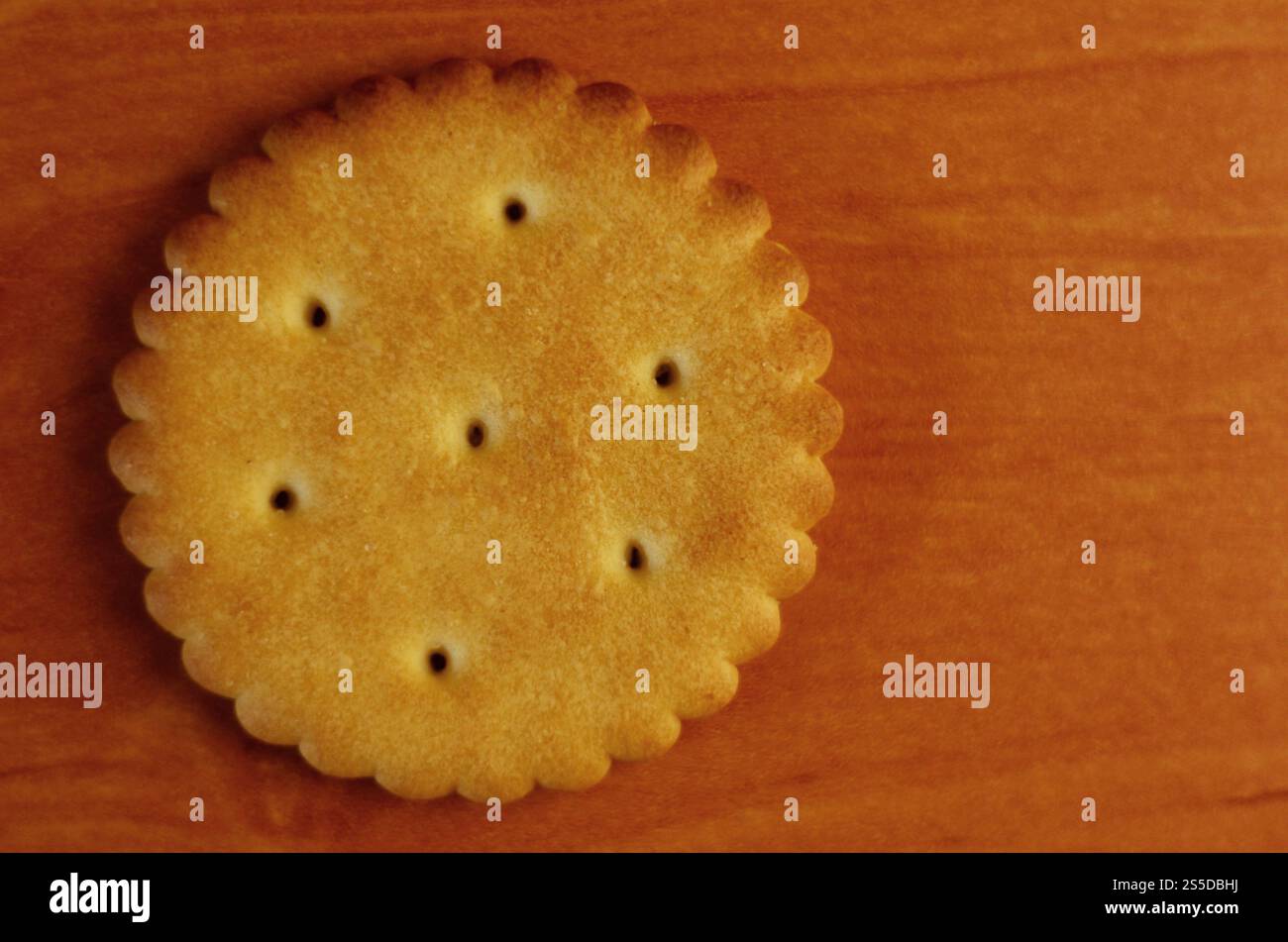 Background image of one classic salty cracker on a brown wooden table ...