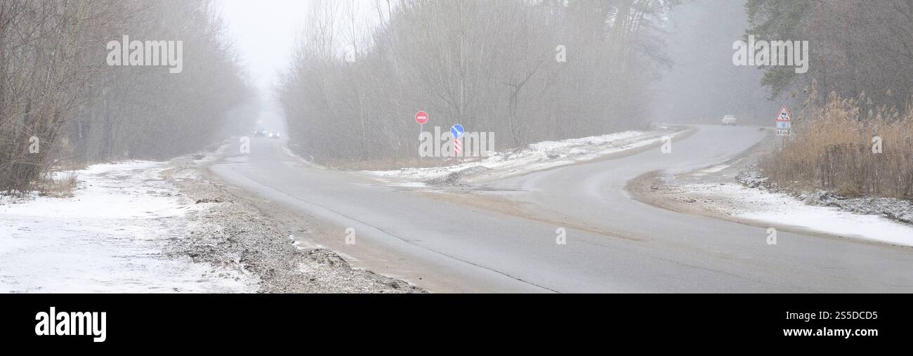 Crossroads on a suburban asphalt road in wintertime during a blizzard ...