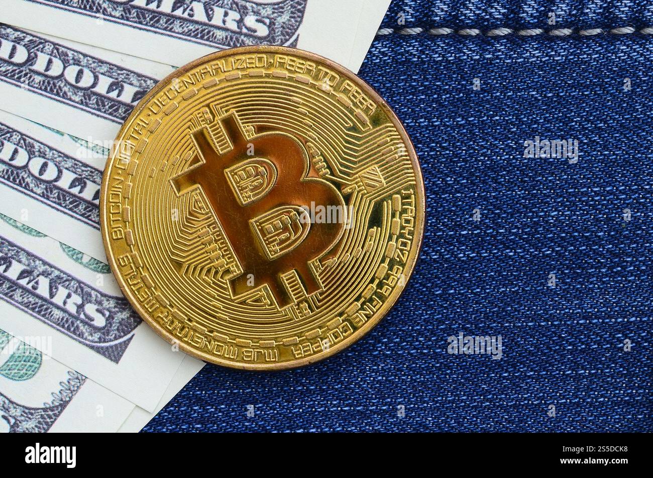 Golden Bitcoin and dollar bills lies on a blue jeans fabric. New ...