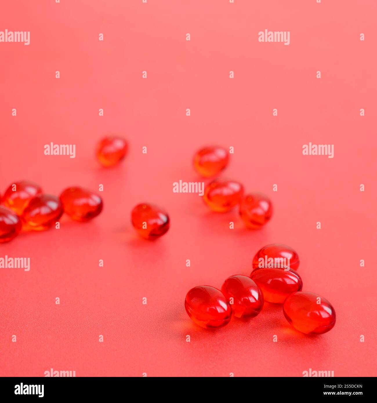 A lot of transparent red tablets lie on the red surface Stock Photo - Alamy