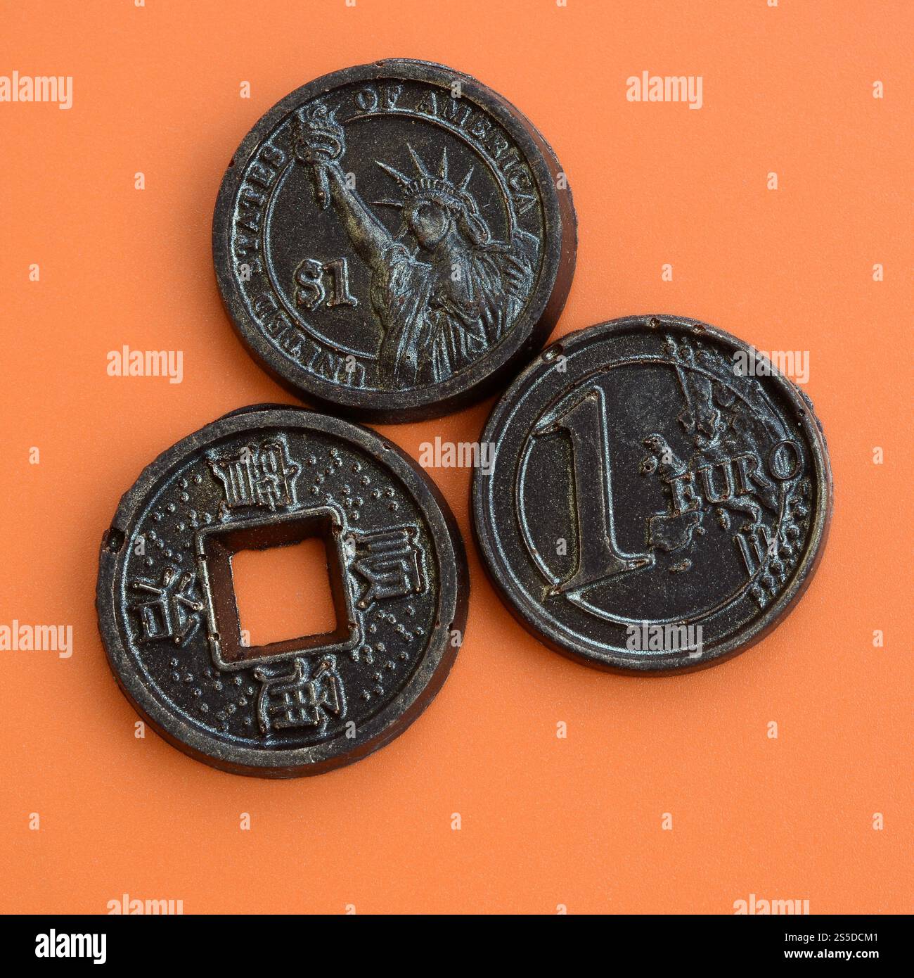 Three chocolate products in the form of Euro, USA and Japan coins lie ...