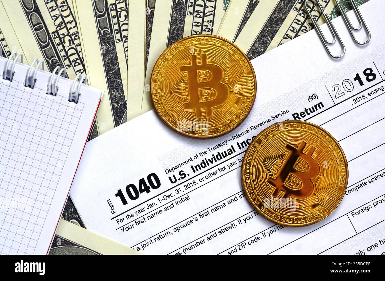 The pen, bitcoins and dollar bills is lies on the tax form 1040 U.S ...
