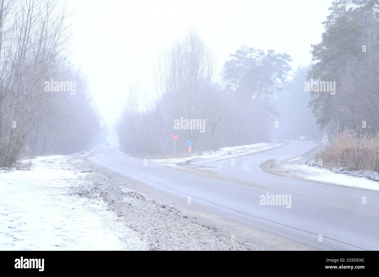 Crossroads on a suburban asphalt road in wintertime during a blizzard ...