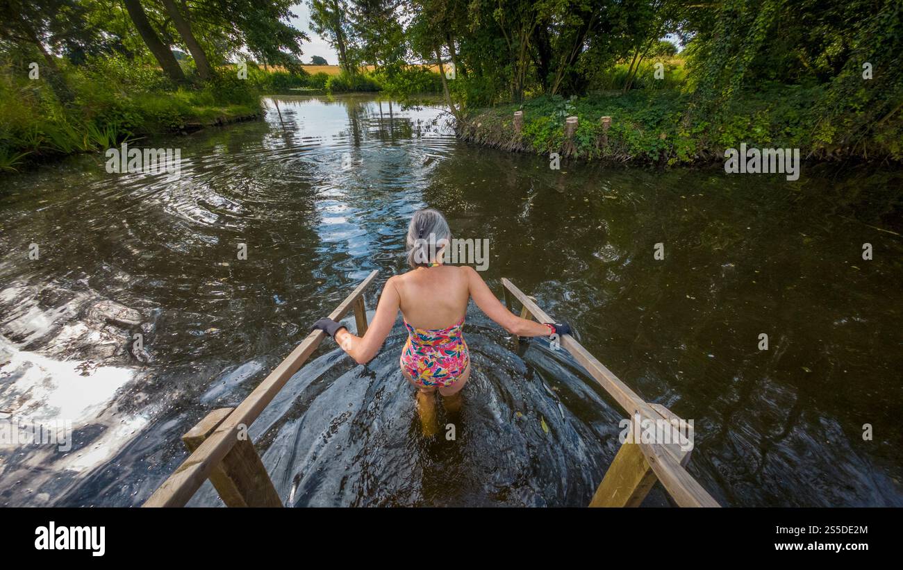 Rear view of female wild swimmer wearing a brightly coloured bathing ...