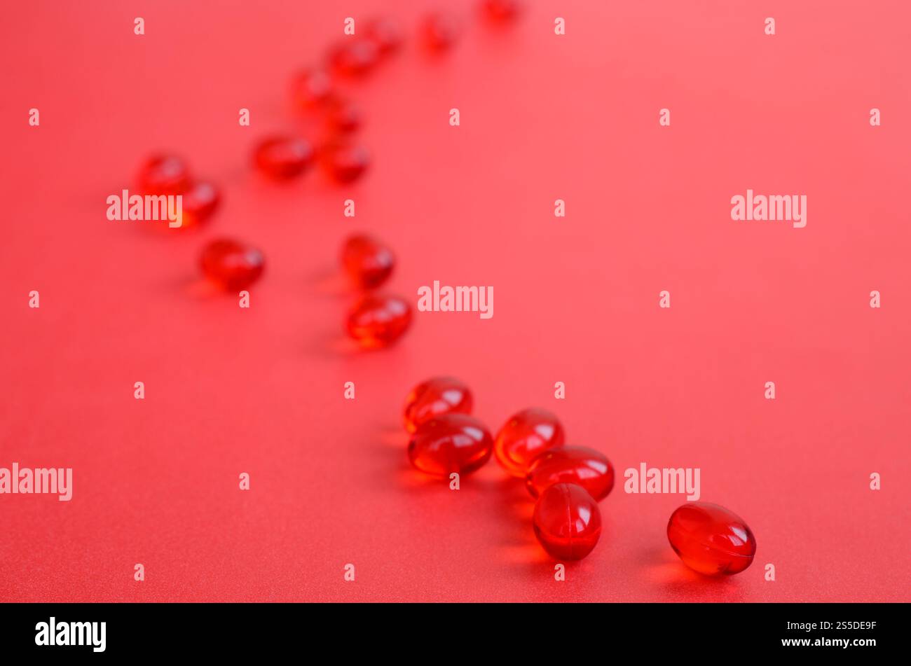 A lot of transparent red tablets lie on the red surface Stock Photo - Alamy