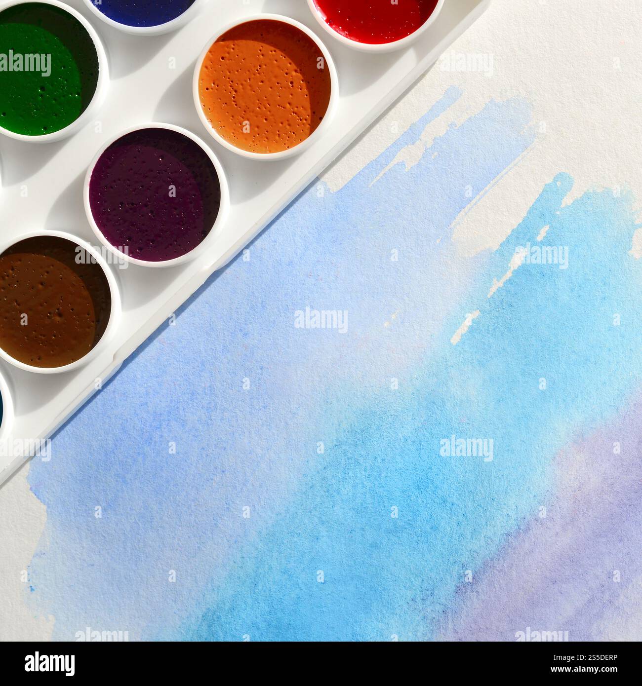 A new set of watercolors lies on a sheet of paper, which shows an ...