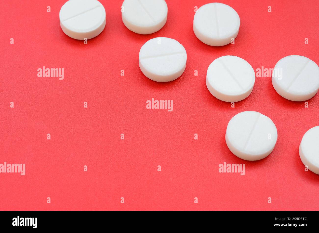 A few white tablets lie on a bright red background surface. Background ...