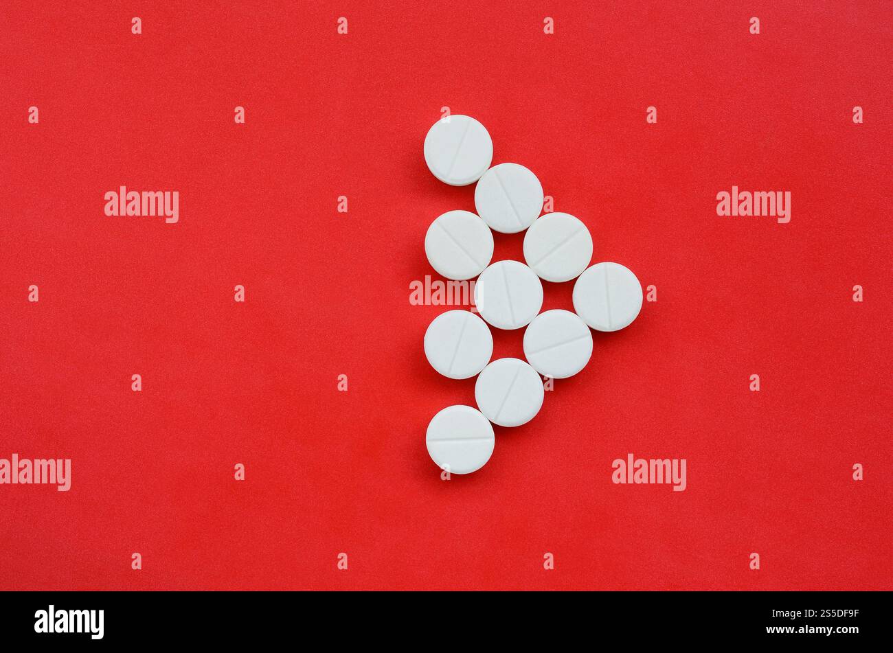 Several white tablets lie on a bright red background in the form of a ...