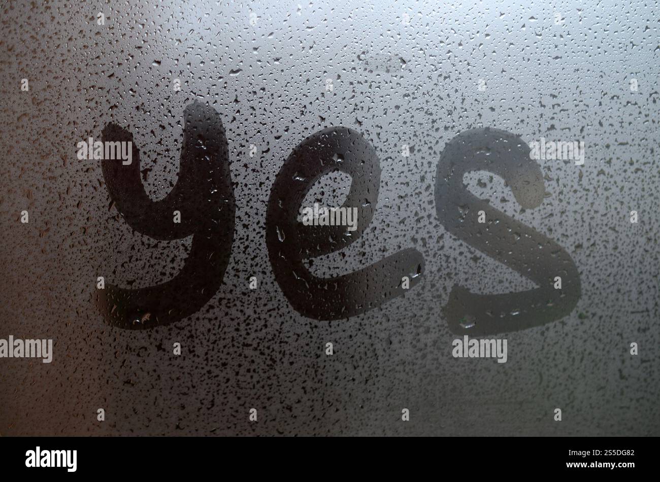 The English word "Yes" is written with a finger on the surface of the ...