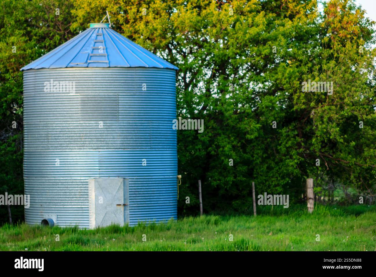 A large metal container with a green roof sits in a grassy field. The ...