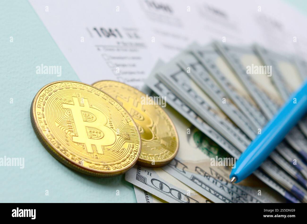 Bitcoins lies with the tax forms and hundred dollar bills on a light ...