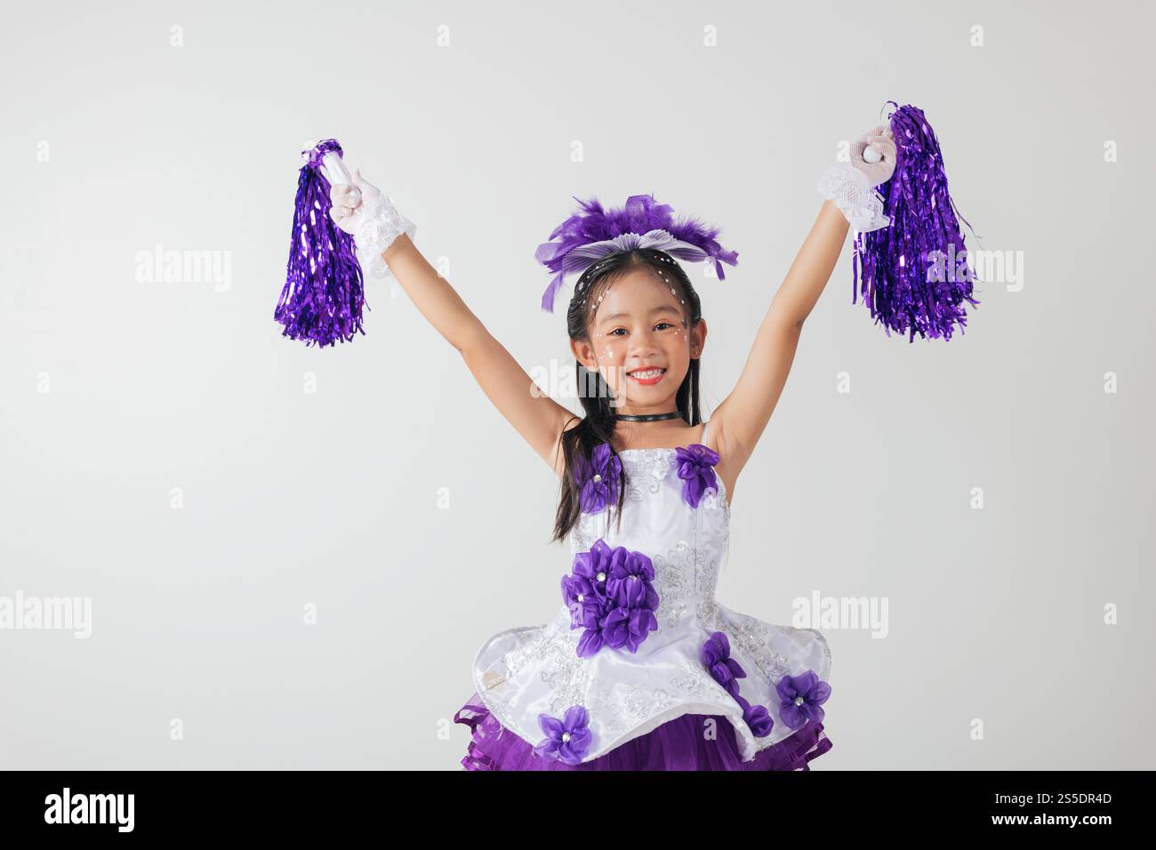 Portrait of a cheerful cheerleader girl in a purple and white outfit ...