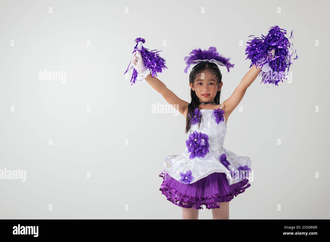 Portrait of a cheerful cheerleader girl in a purple and white outfit ...