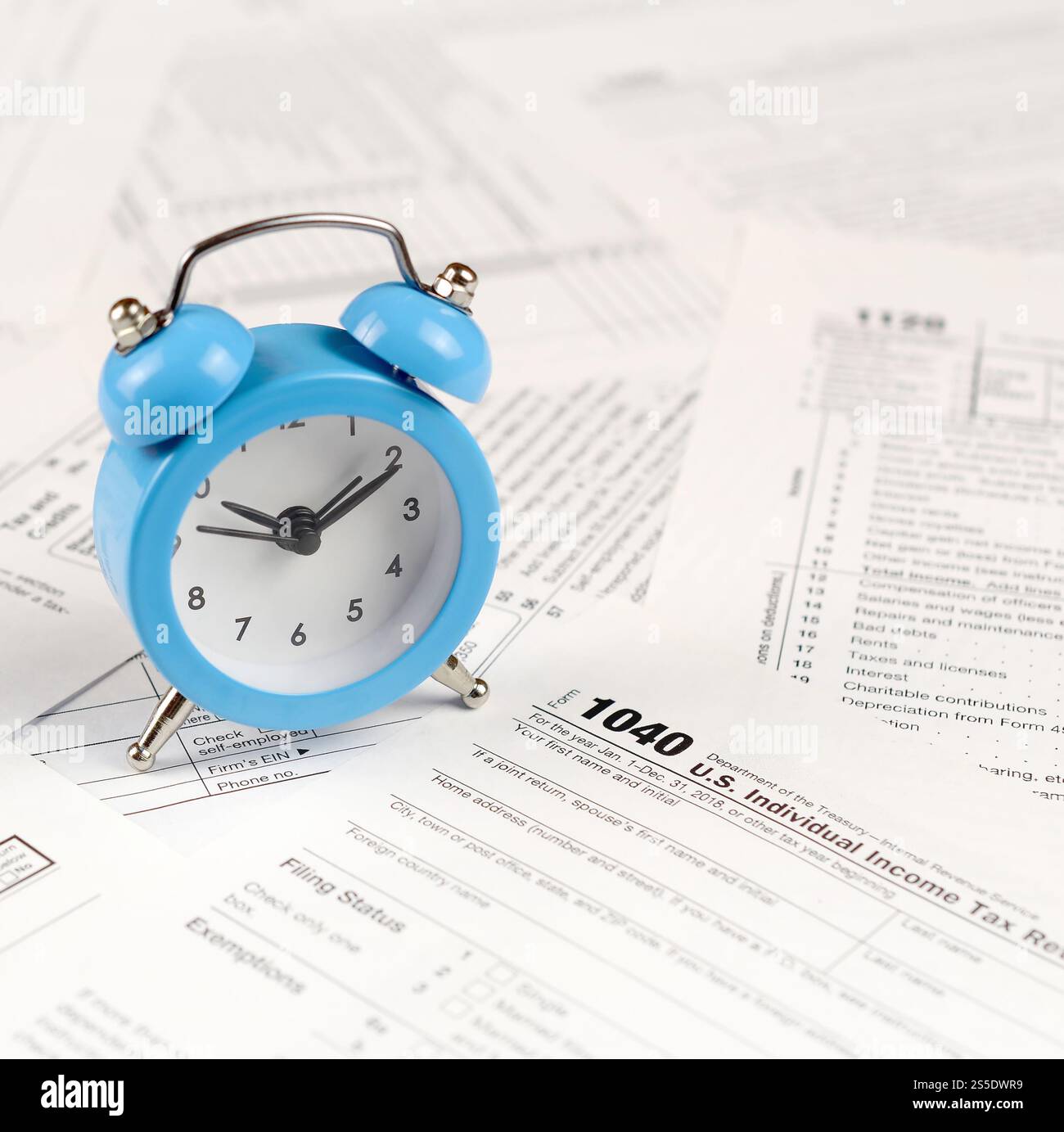 1040 Individual income tax return form with blue alarm clock. Concept ...