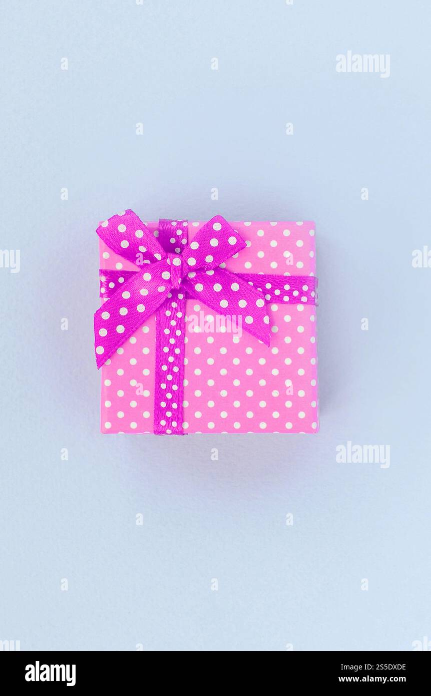 Small purple gift box with ribbon lies on a violet background ...