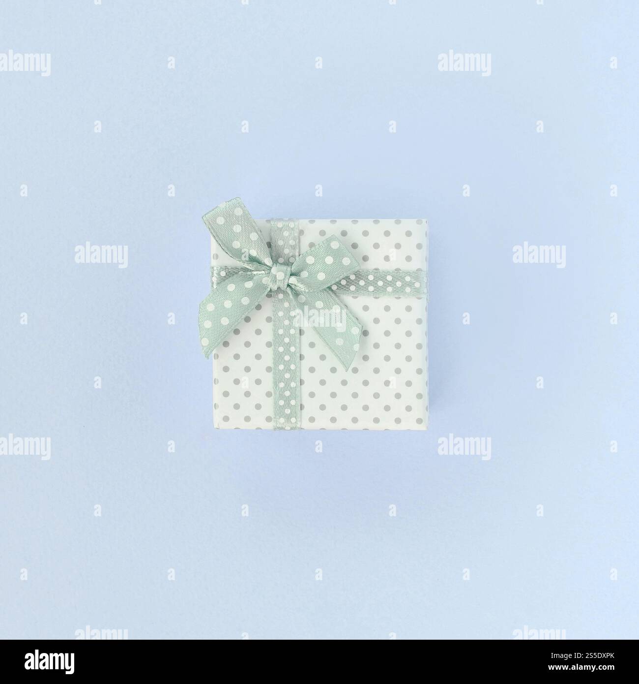 Small white gift box with ribbon lies on a violet background ...