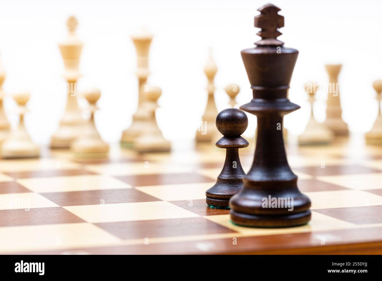 black pawn and queen against white chess pieces in background on wooden ...
