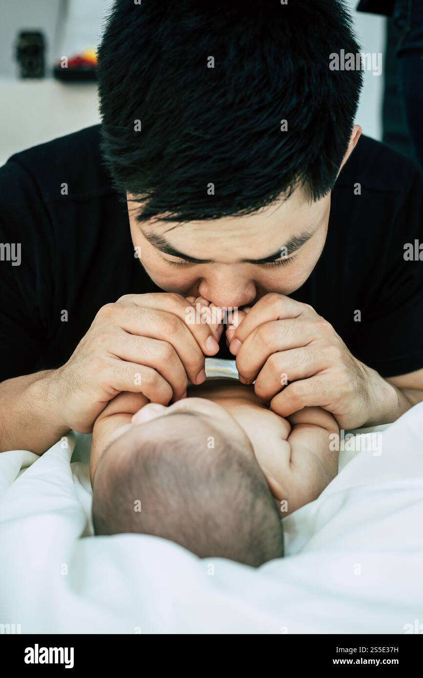 A young Asian father is sniffing his newborn baby Stock Photo - Alamy