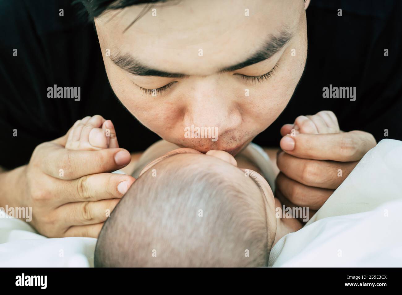 A young Asian father is sniffing his newborn baby Stock Photo - Alamy