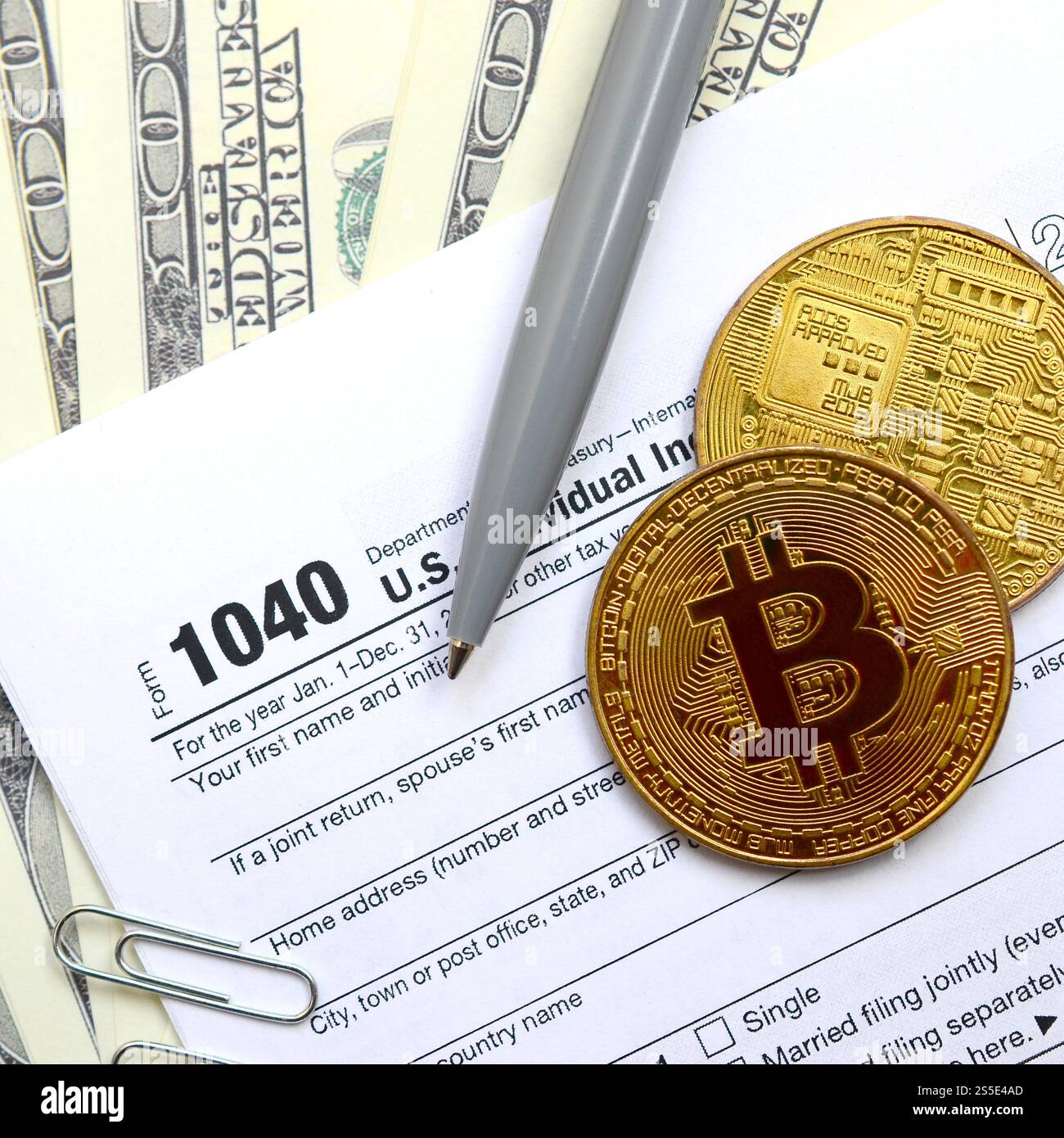 The pen, bitcoins and dollar bills is lies on the tax form 1040 U.S ...