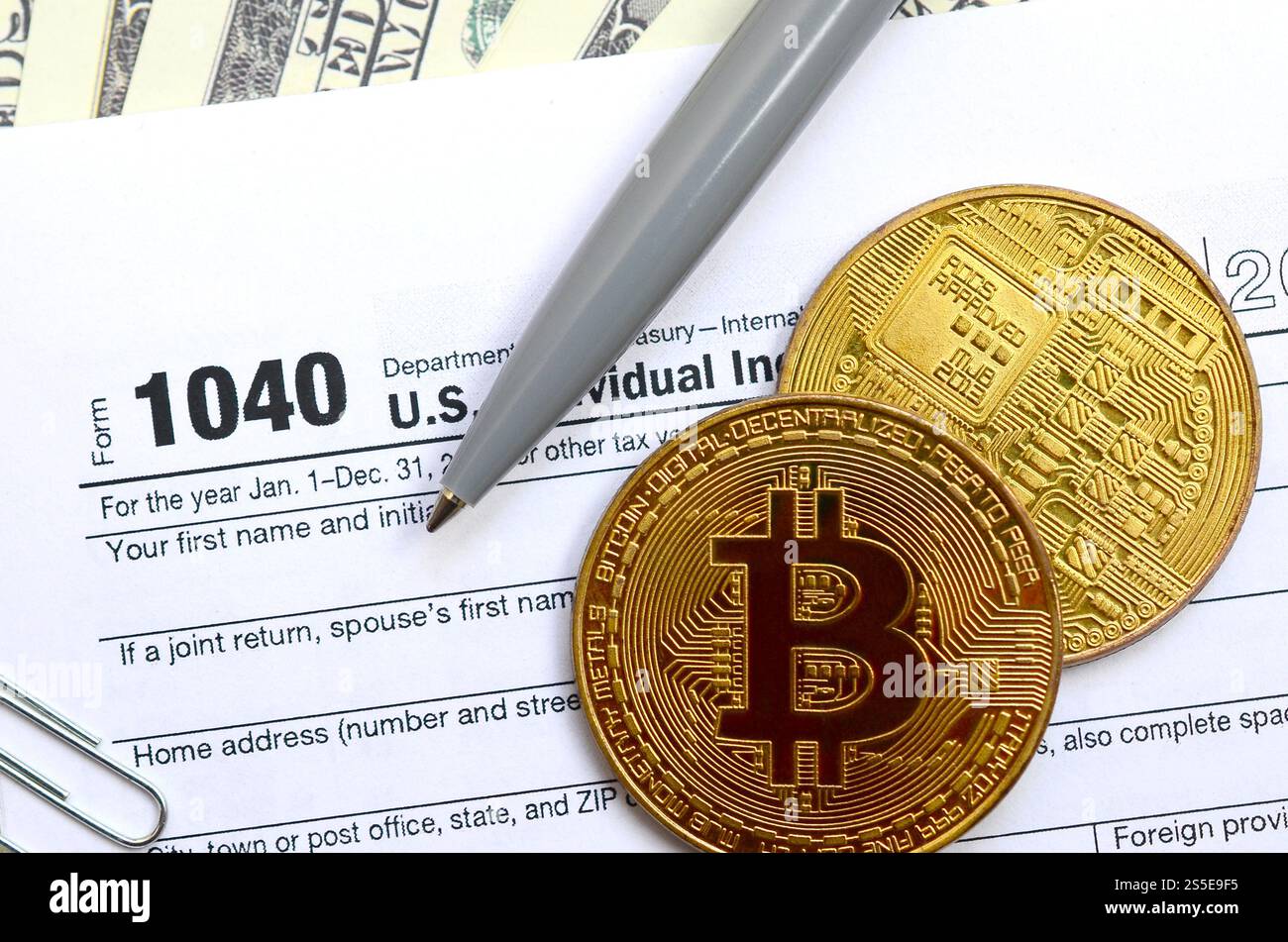The pen, bitcoins and dollar bills is lies on the tax form 1040 U.S ...